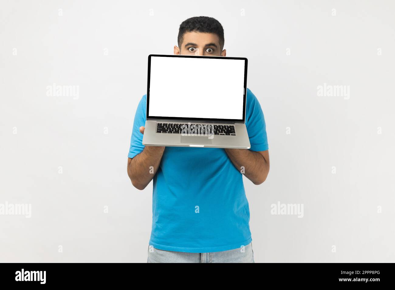 Portrait of shy young adult man wearing blue T- shirt standing hiding ...