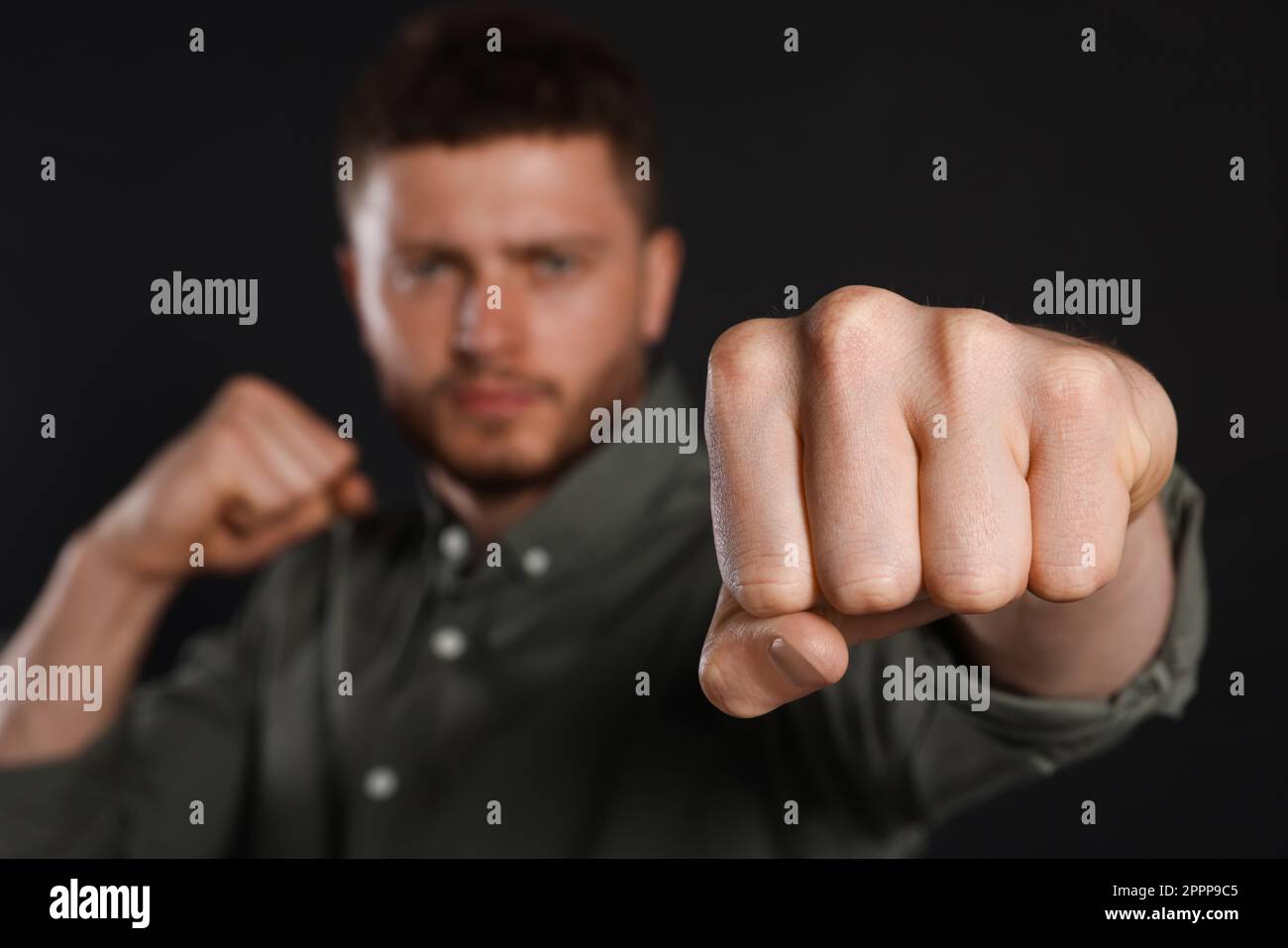 Young man ready to fight against black background, focus on hand. Space ...