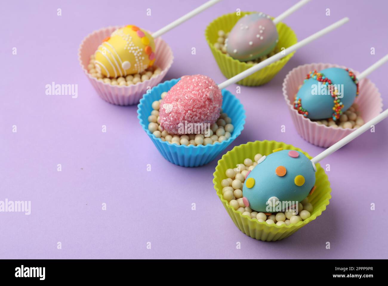 Egg shaped cake pops for Easter celebration on violet background Stock ...