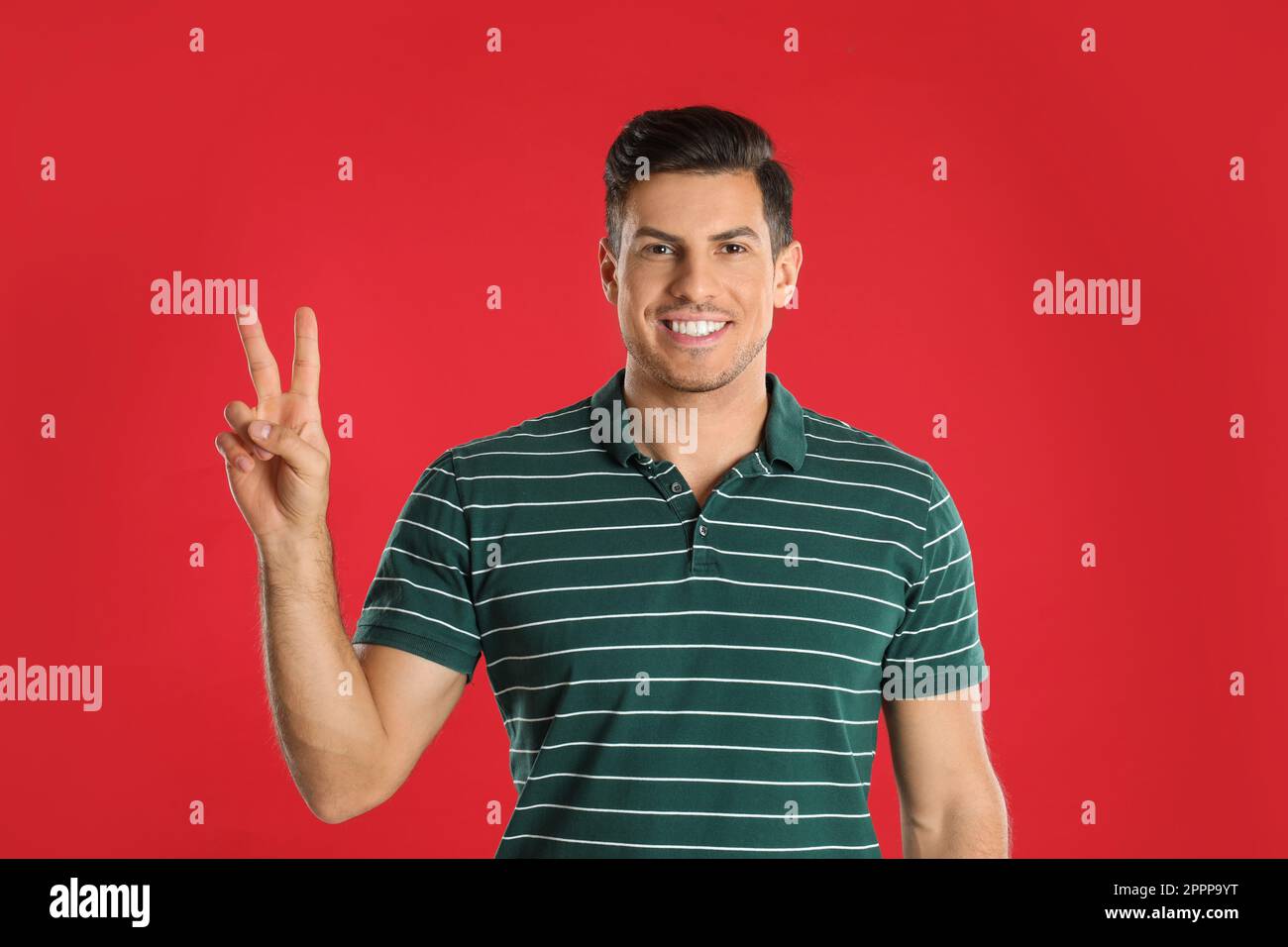 Man showing number two with his hand on red background Stock Photo - Alamy