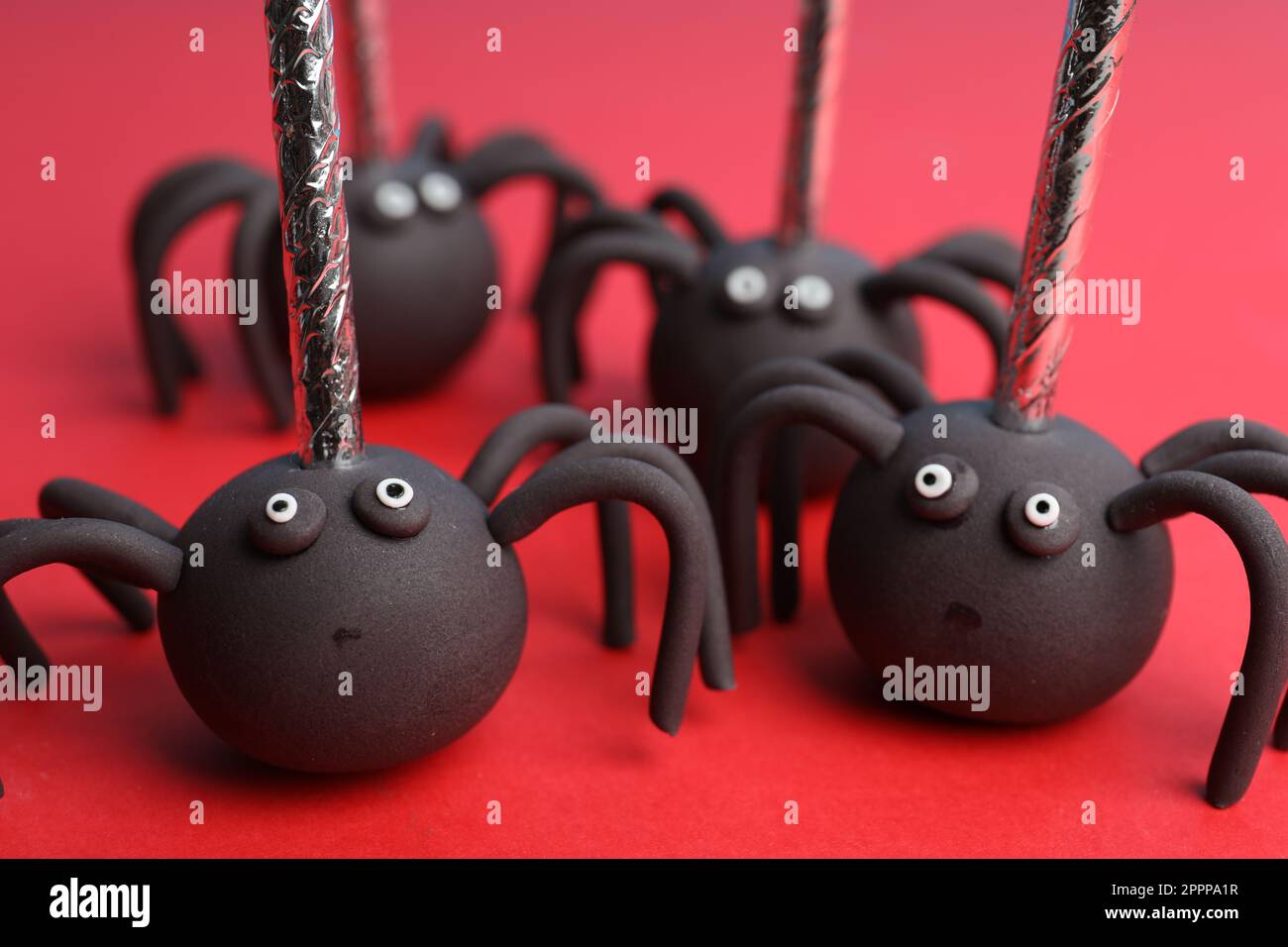Delicious spider shaped cake pops on red background, closeup. Halloween ...