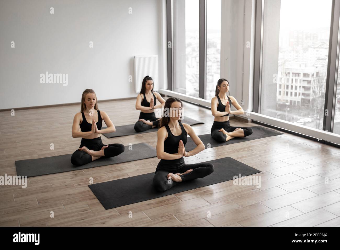 Group of athletic caucasian women in sports clothes breathing in lotus ...