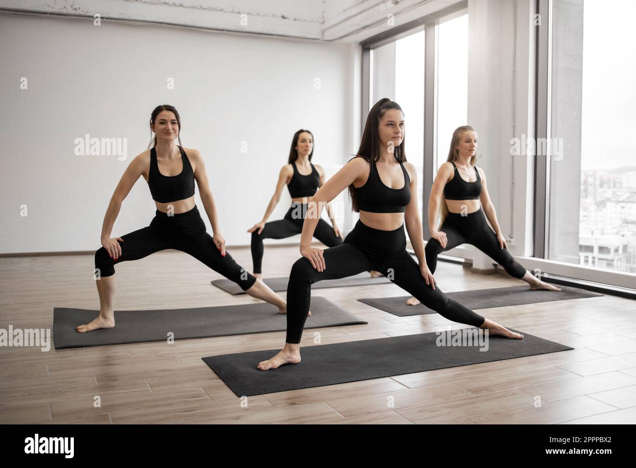Group of young athletic people in black sportswear stretching muscles ...