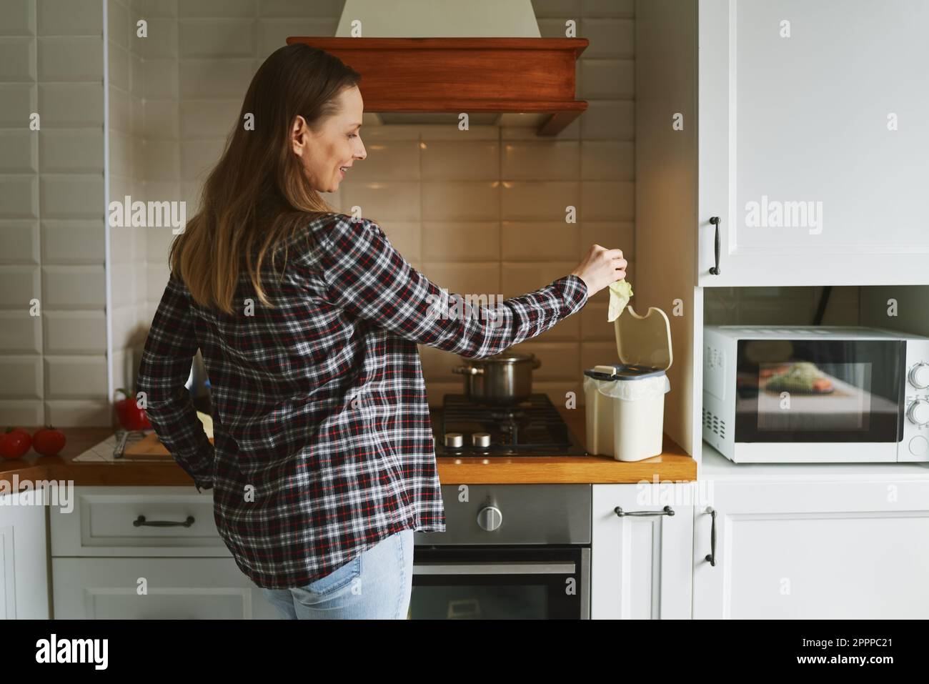 Woman throwing organic food leftovers in a compost bin for recycling ...
