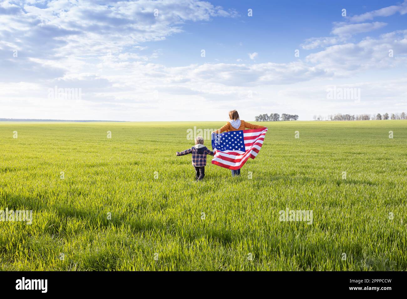 woman and child have fun running on green grass with an American flag ...