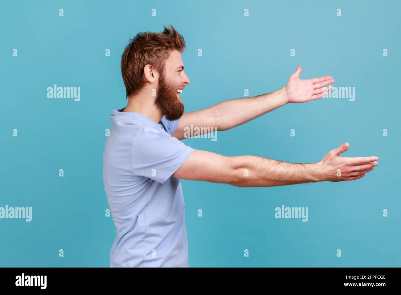 Free hugs, come into my arms. Side view of happy bearded man stretching ...