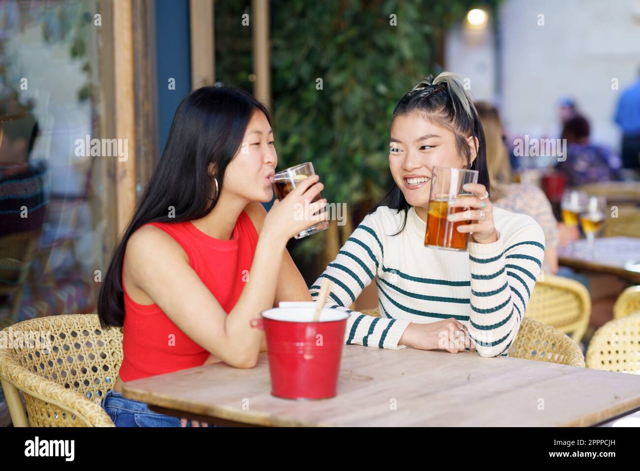 Smiling Asian friends drinking fresh beverages in cafe Stock Photo - Alamy