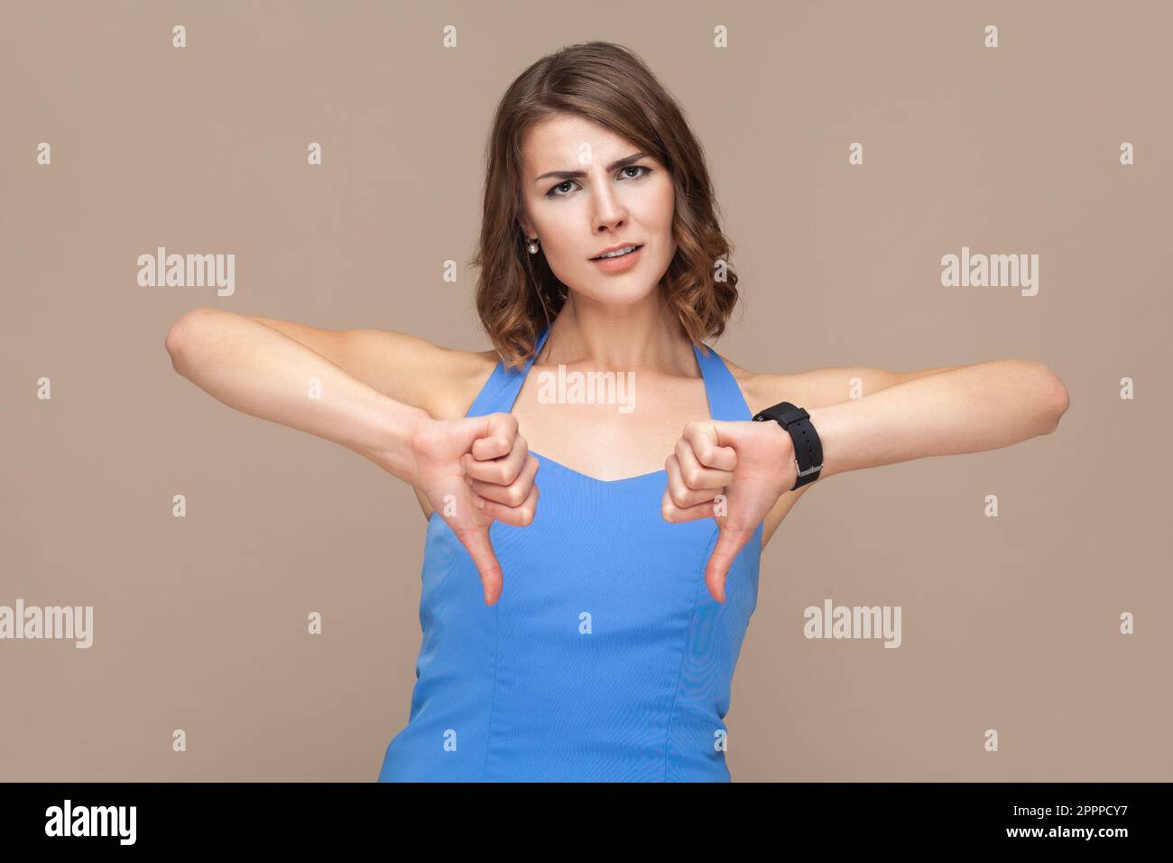 Attractive disappointed woman with wavy hair keeps thumb down, shows ...