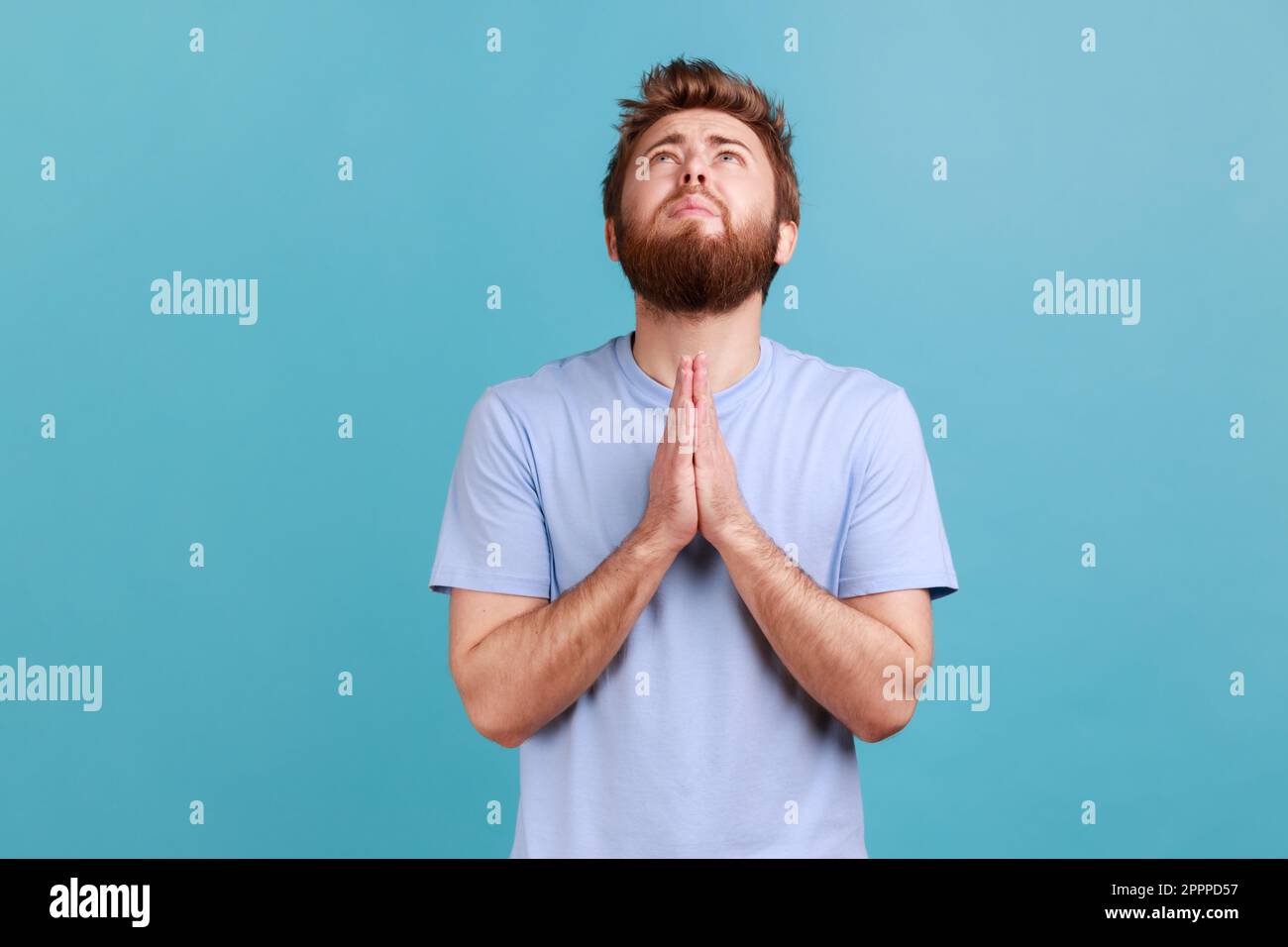 Portrait of hopeless desperate bearded man folding hands in pray ...