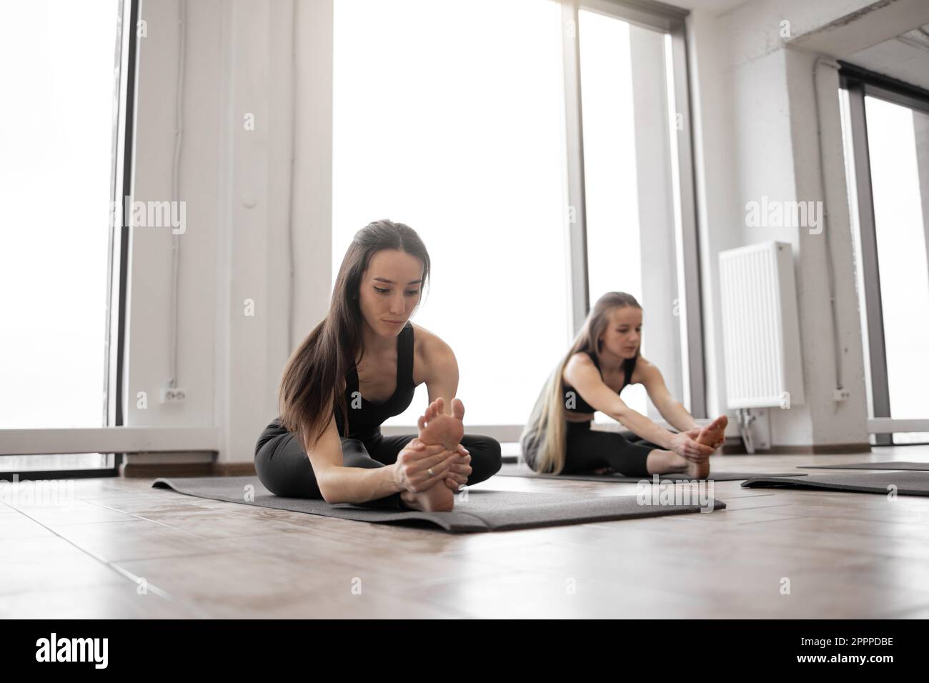 Healthy yoga people in sports clothes exercising Janu Sirsasana on ...