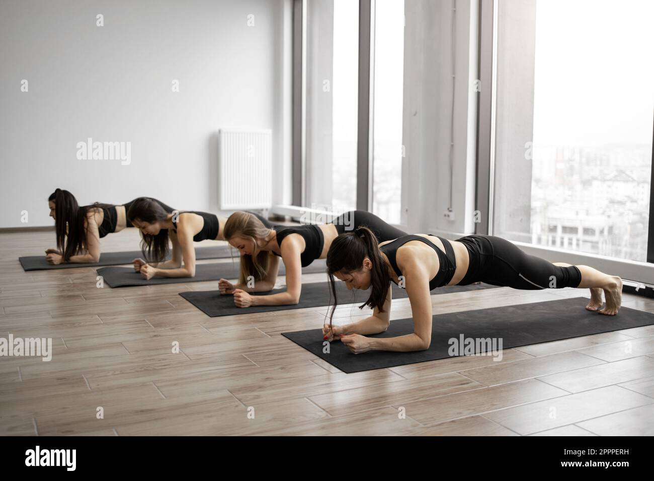 Athletic young females strengthening whole body with Forearm Plank Pose ...