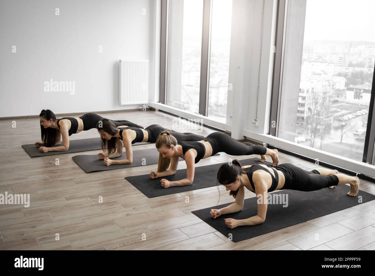 Athletic young females strengthening whole body with Forearm Plank Pose ...