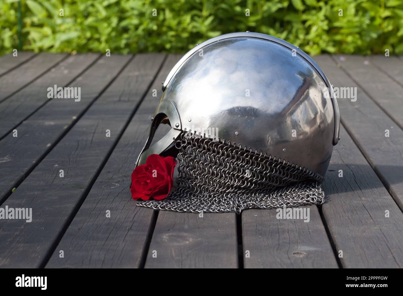 Steel, Viking Knight helmet on a balcony floor. Red rose on this side ...