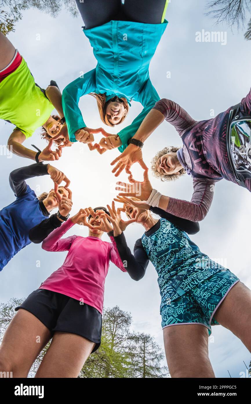 Group of female athletes runners in circle forming hearts with hands ...
