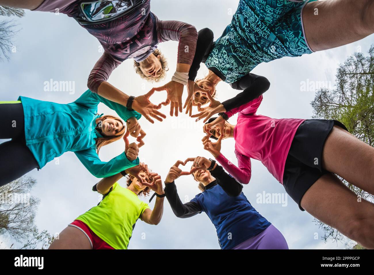 Group of female athletes runners in circle forming hearts with hands ...