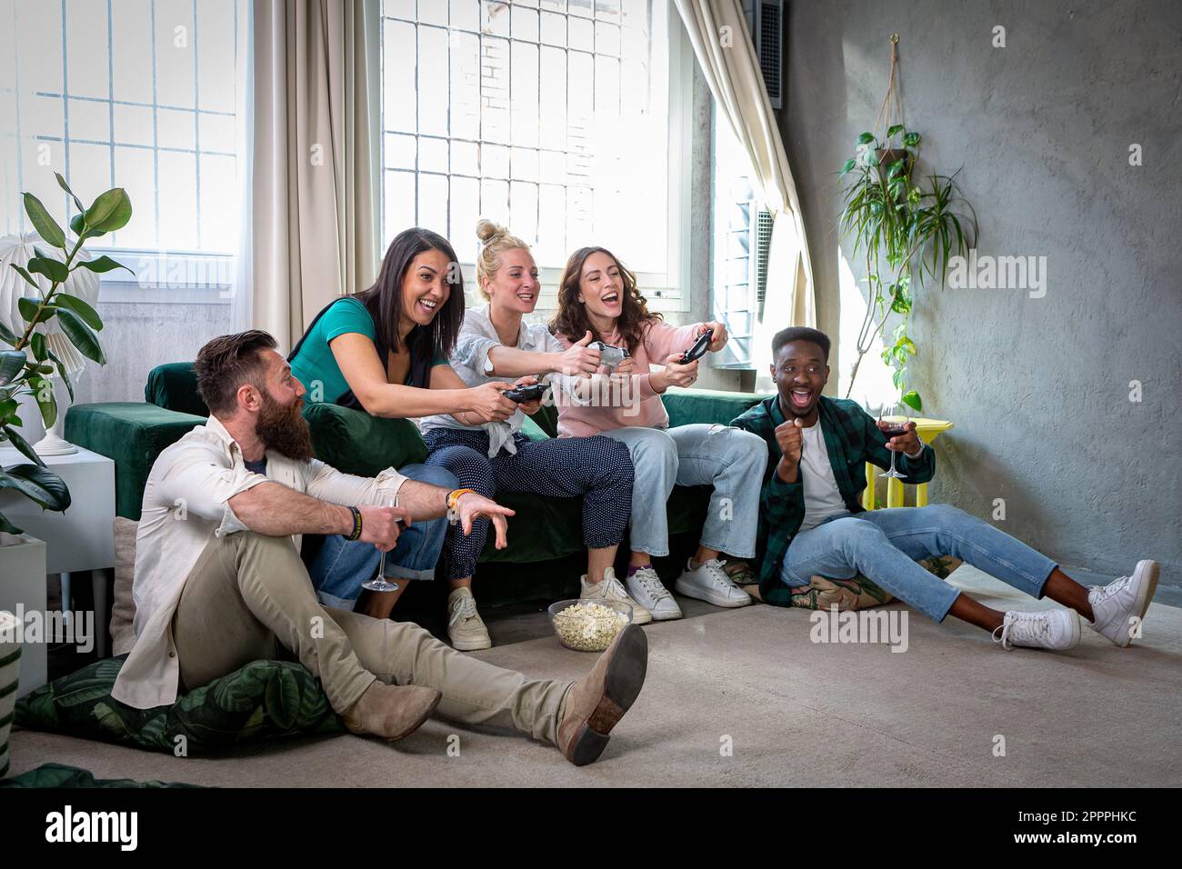 Group of young friends playing video games on the sofa in the living ...