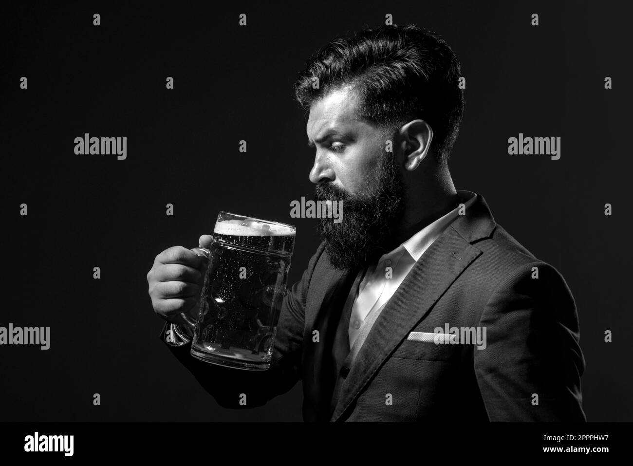 Man in classic suit drinking beer. Bearded guy in business outfit looks ...