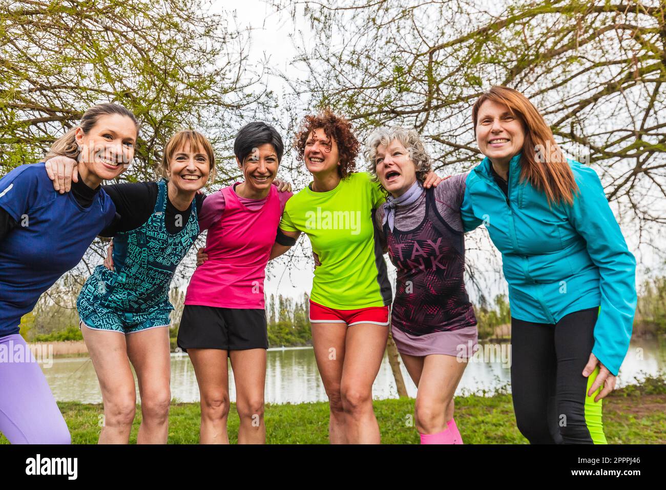 Mixed group of female athletes laughing and smiling in embrace after ...