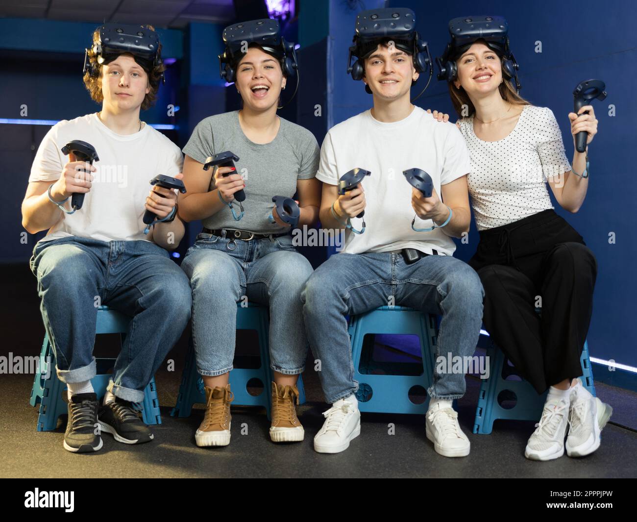 four smiling students with virtual reality devices sit and pose in ...