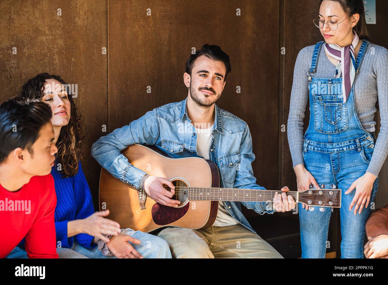 Moment of relaxation among friends in which a boy plays the guitar ...