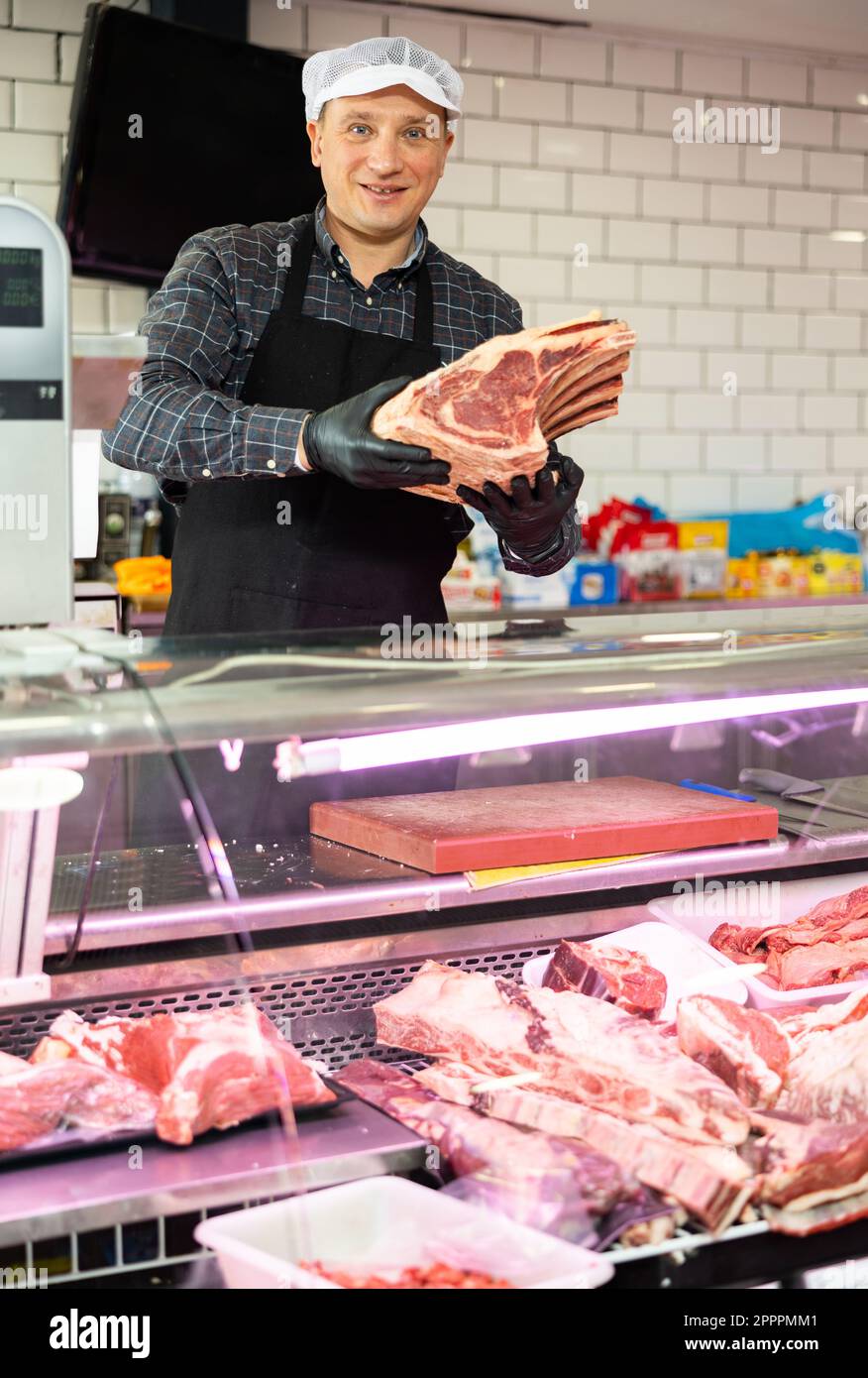 Adult man puts beef ribs in showcase Stock Photo - Alamy