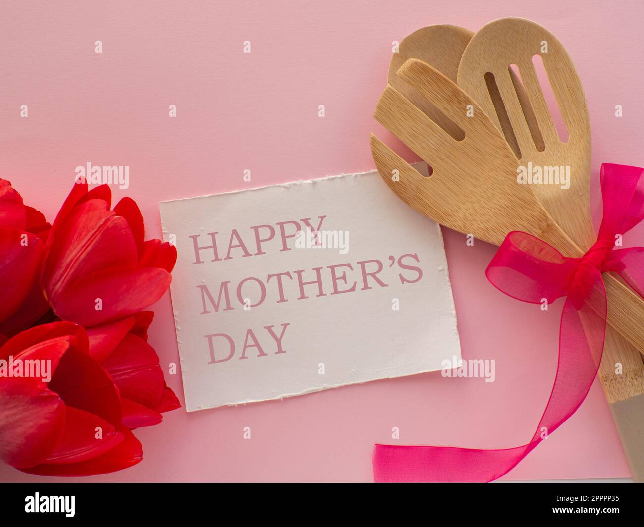 Red tulips flowers with kitchen tools on pink background with white ...