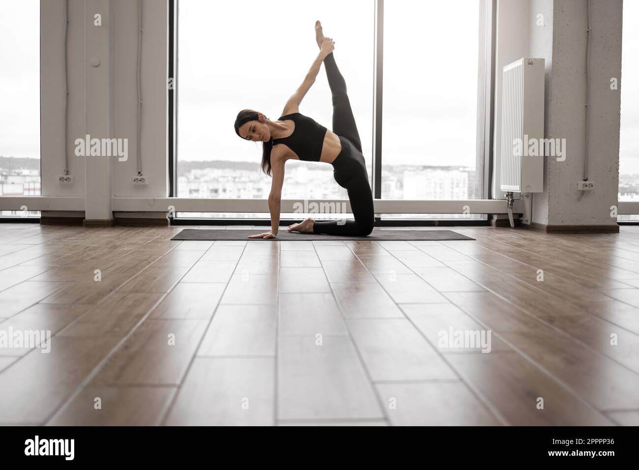 Flexible caucasian woman in black activewear with sportive body doing ...