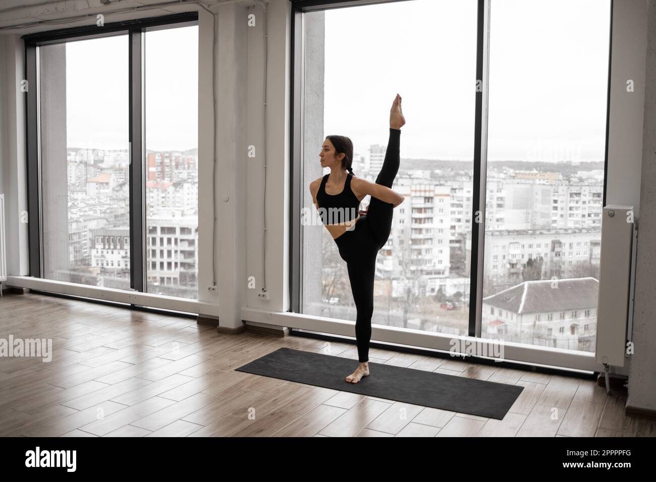 Caucasian dark-haired woman practicing advanced yoga standing in ...