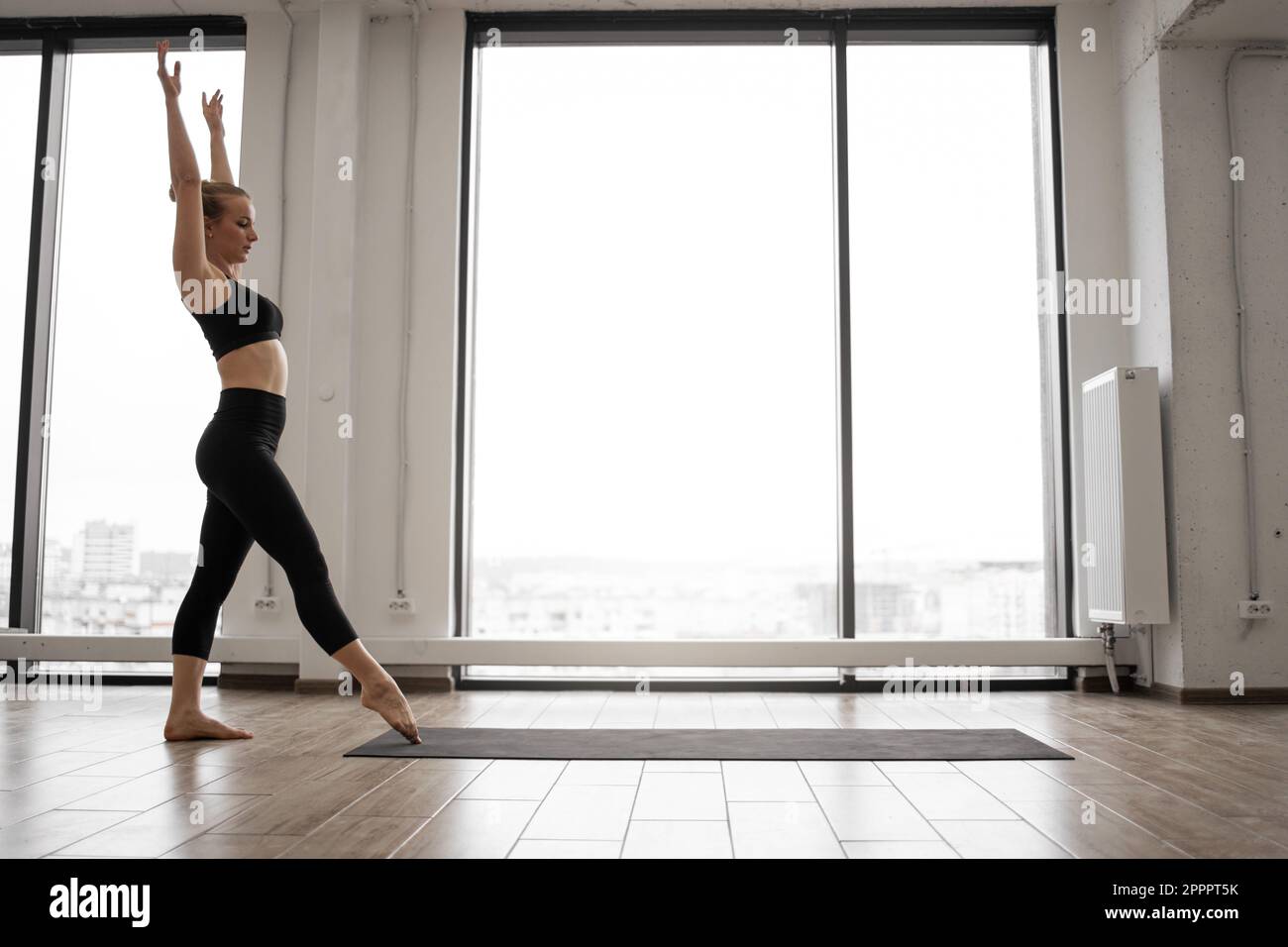 Beautiful light-haired lady in black sportswear being engaged in ...