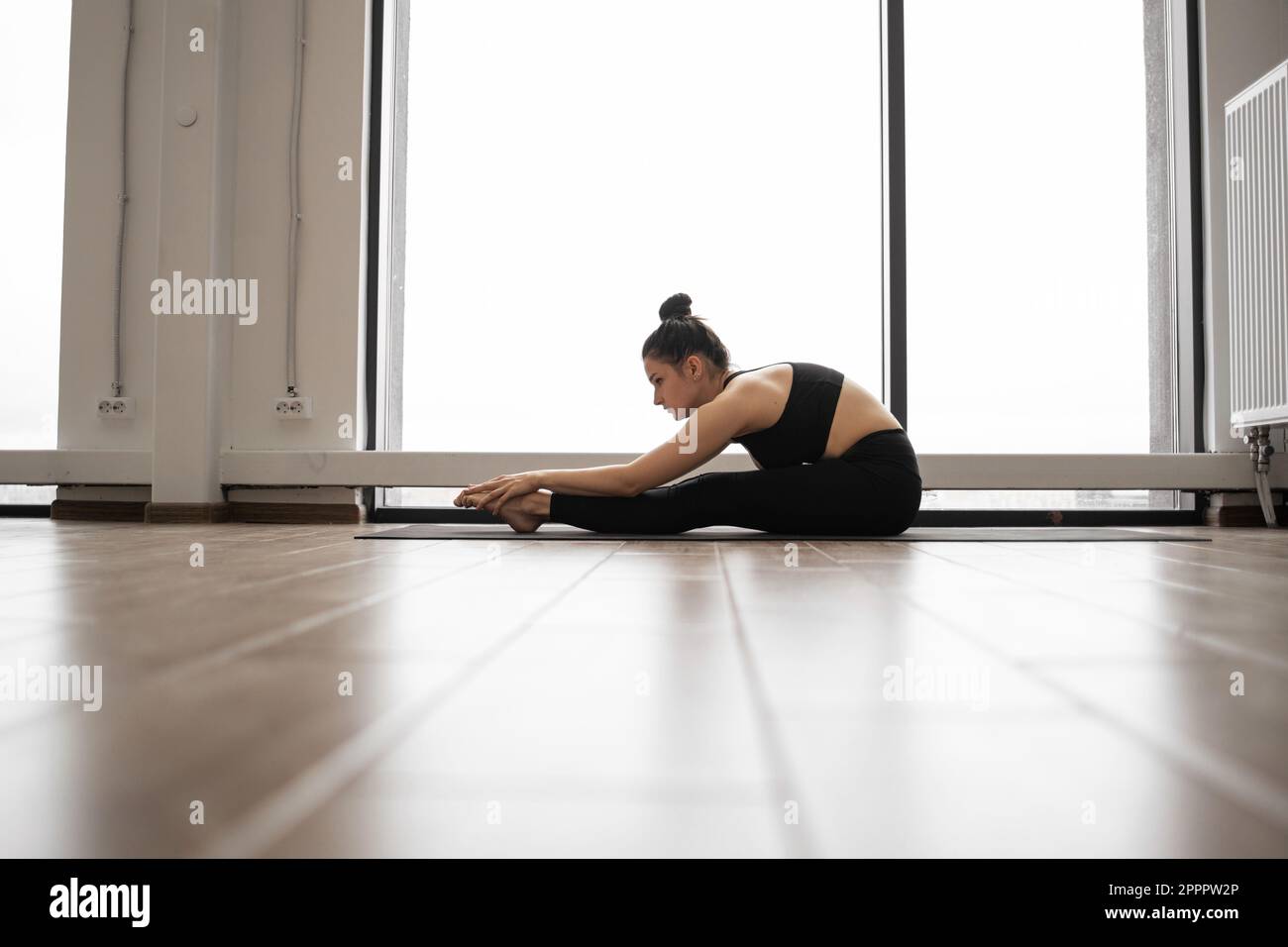 Side view of bendy young brunette having stretching workout on yoga mat ...