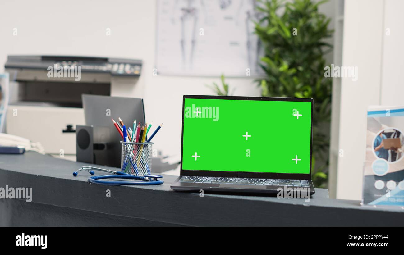 Laptop with blank green screen template at front desk, empty hospital ...