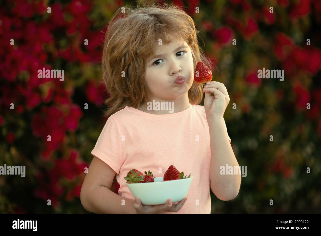 Kids funny face. Cute child eating strawberries Stock Photo - Alamy