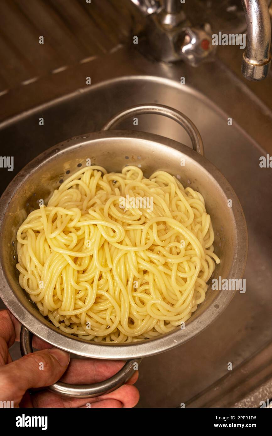 Spaghetti being poured into a colander. vertical photo Stock Photo - Alamy