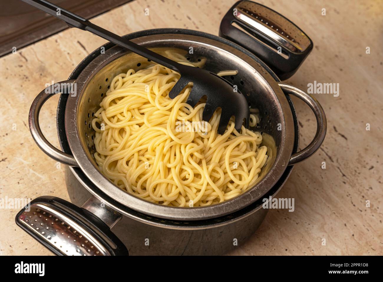boiled ready-made spaghetti in a colander and a kitchen saucepan Stock ...