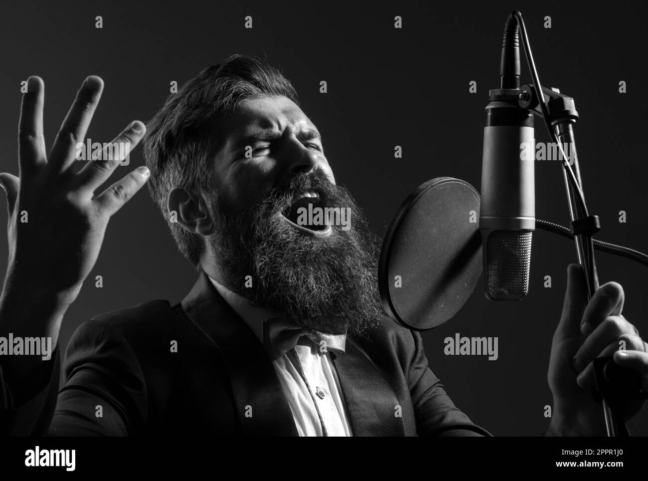 Classic singer in suit. Man with microphone singing song. Musician in ...