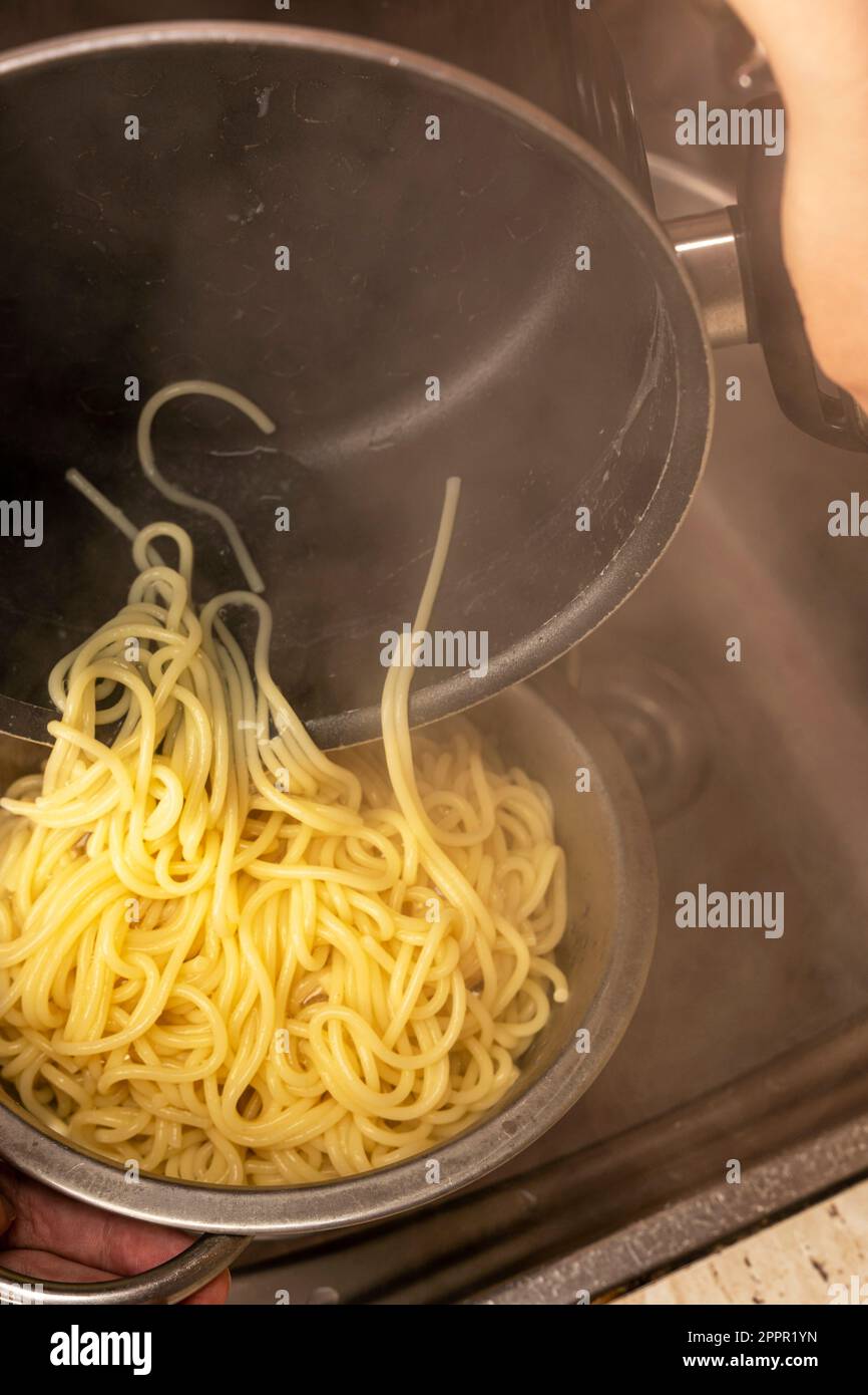 Spaghetti being poured into a colander. vertical photo Stock Photo - Alamy