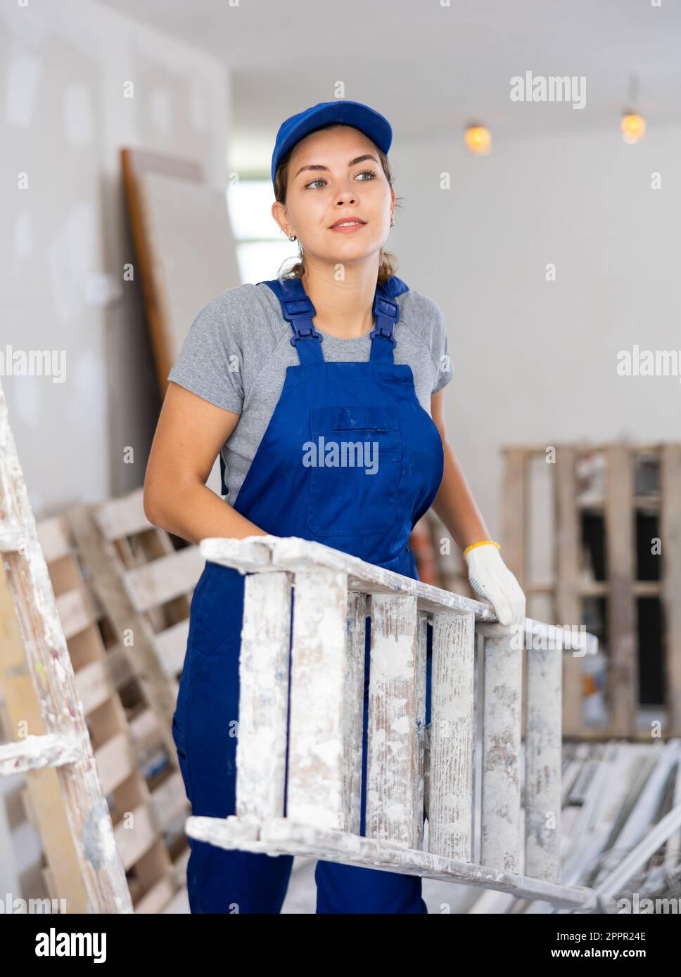 Female construction worker carrying ladder during renovation works ...