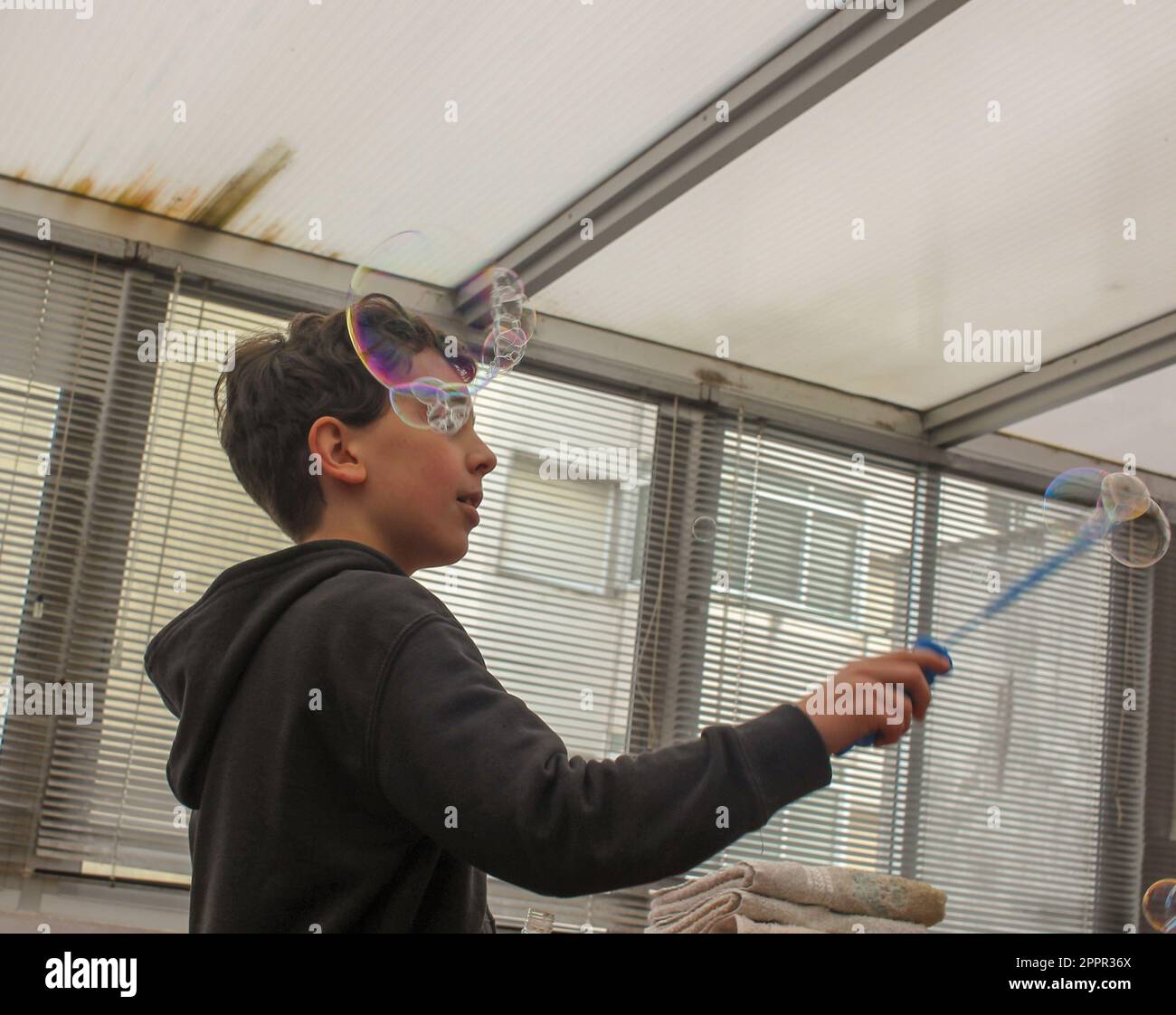 young boy playing with big bubbles near a window at home Stock Photo ...
