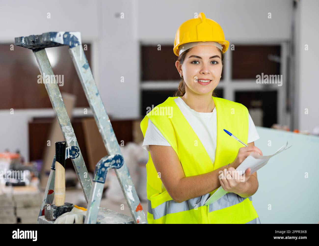 Positive female civil engineer taking notes while checking construction ...
