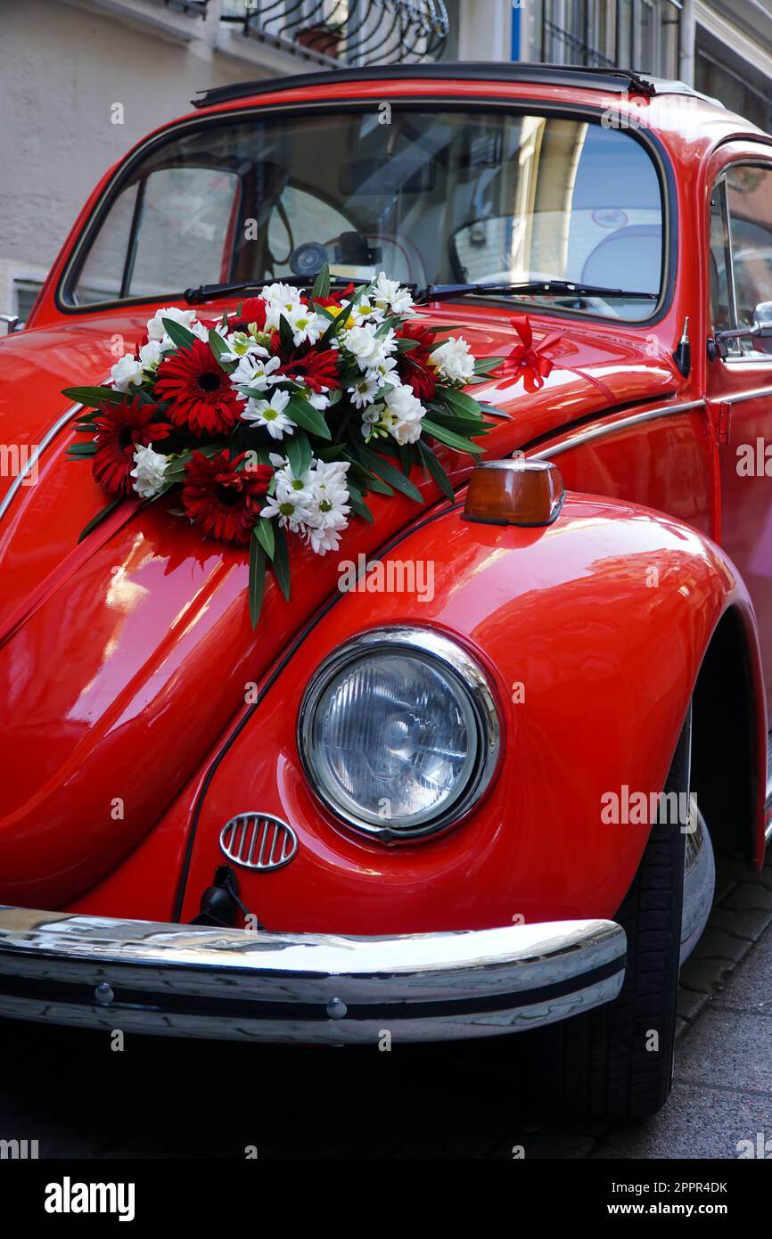 A red vintage German Car is decorated with flowers as a wedding car ...