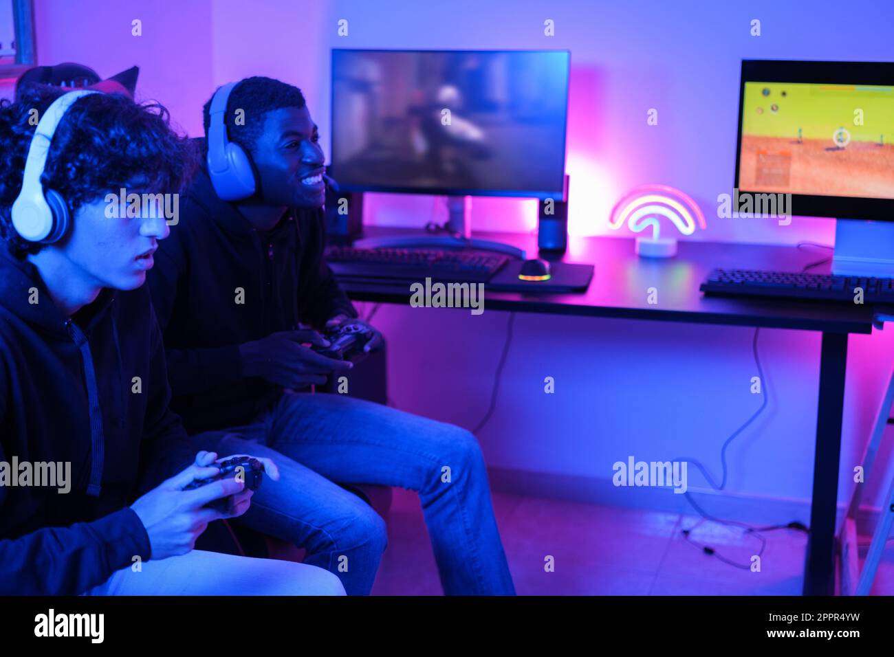 Two young teenagers playing video games online in their gaming room and ...