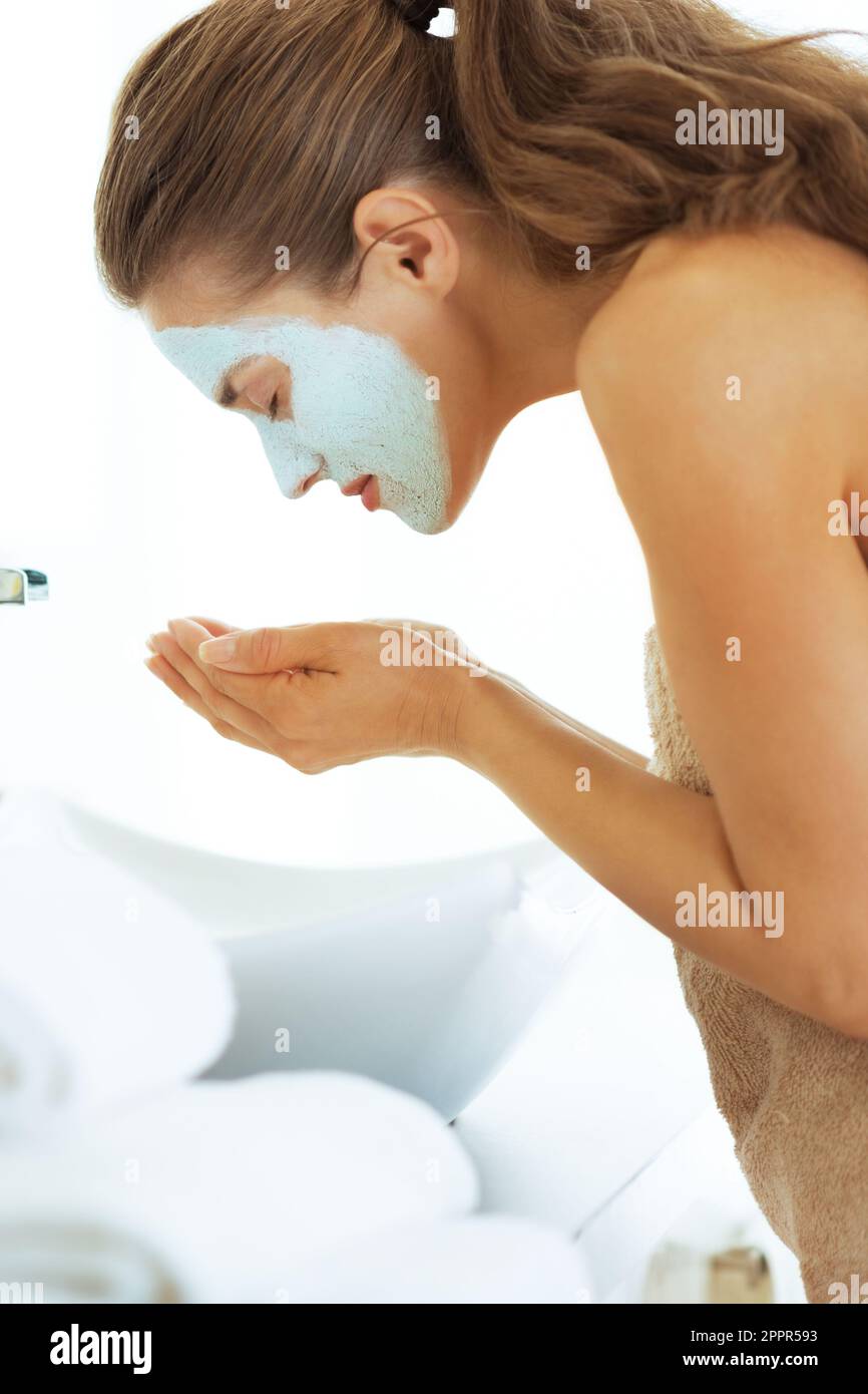Young woman wearing facial cosmetic mask washing face Stock Photo - Alamy