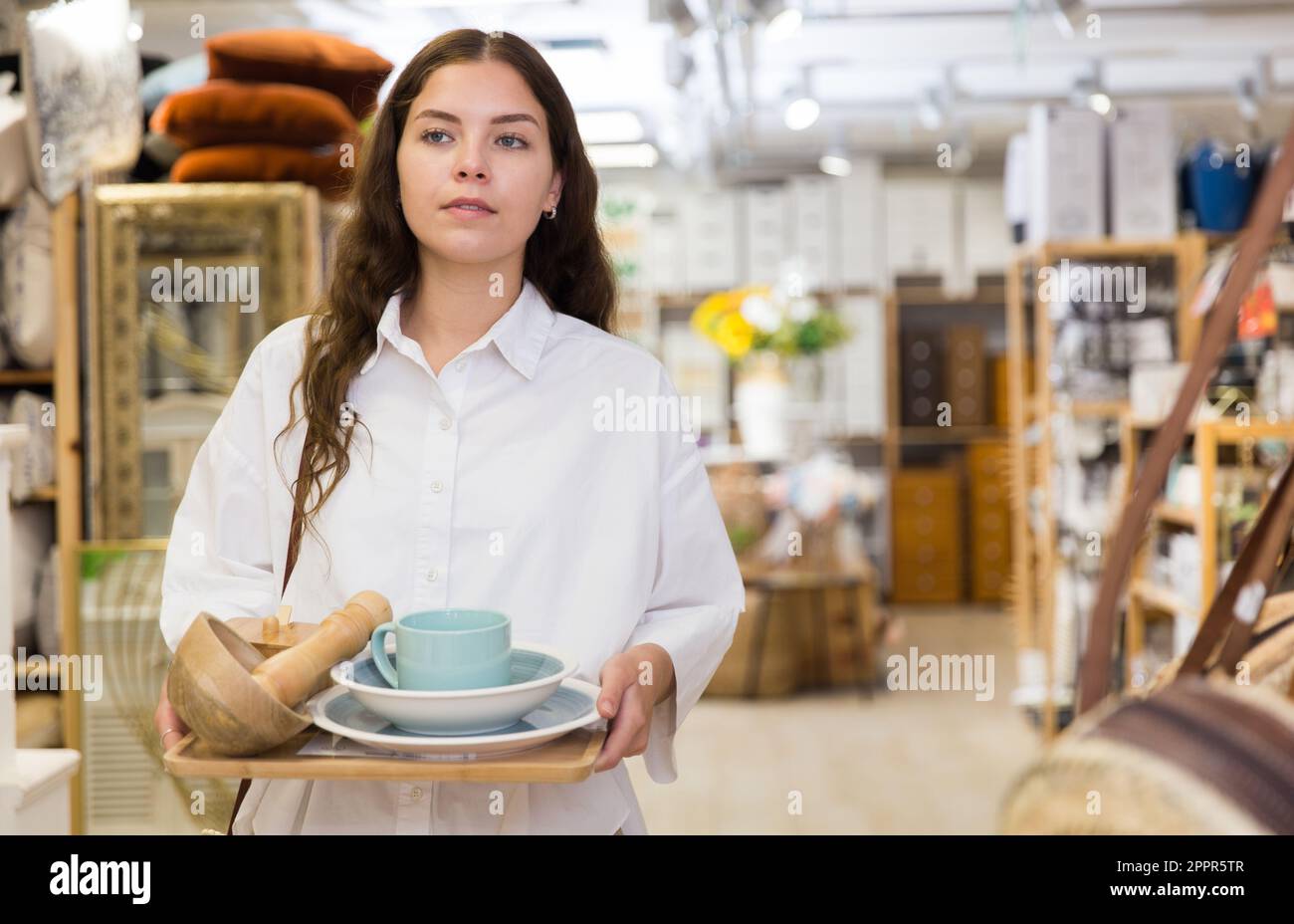 Woman customer holding purchases and walking in household goods store ...
