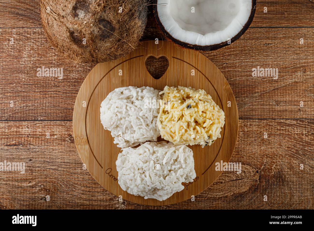 White and yellow cocada two coconuts behind on wooden table, love ...
