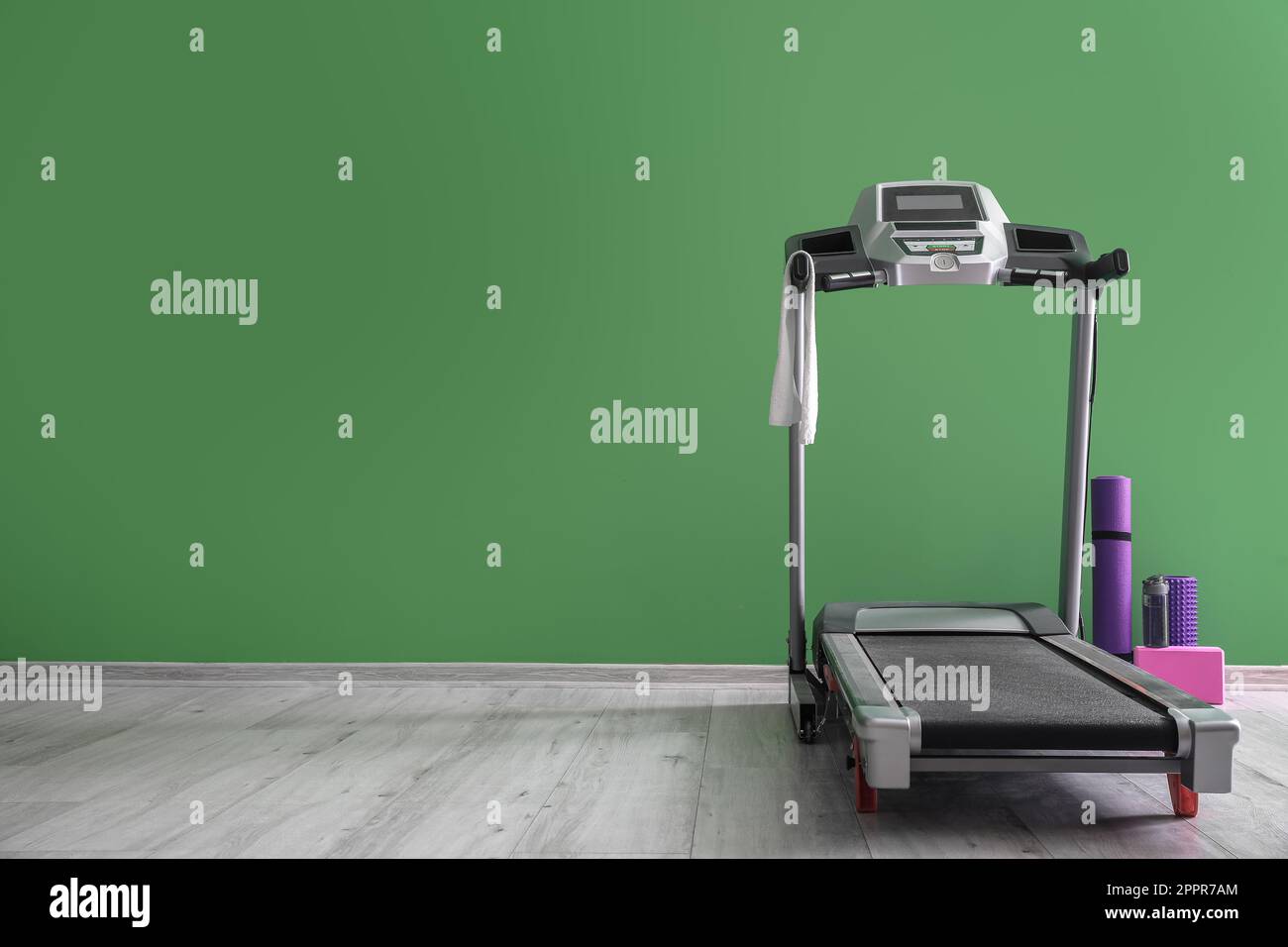 Modern treadmill and sports equipment near green wall Stock Photo - Alamy