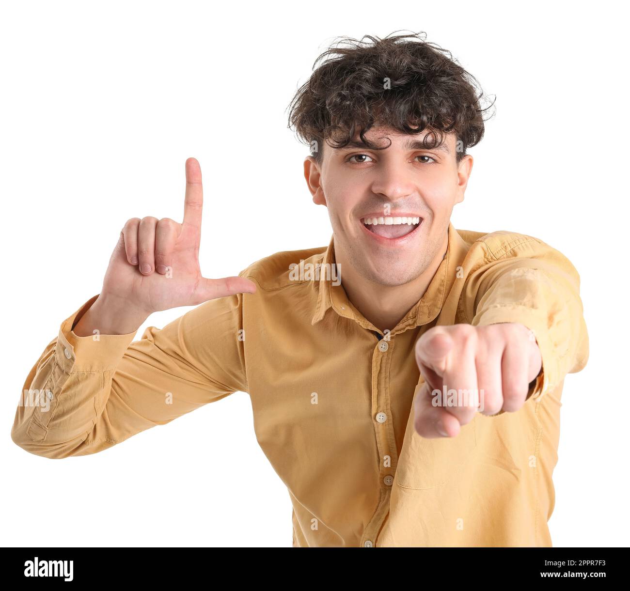 Laughing young man showing loser gesture and pointing at viewer on ...