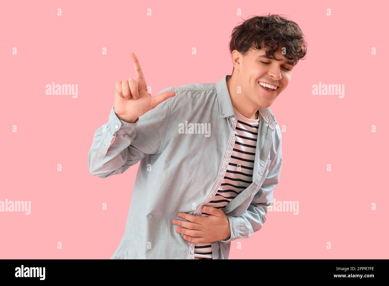 Laughing young man showing loser gesture on pink background Stock Photo ...