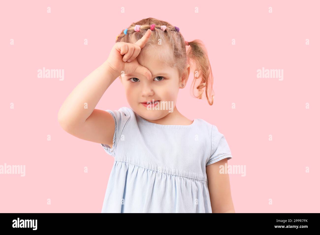 Funny little girl showing loser gesture on pink background Stock Photo ...
