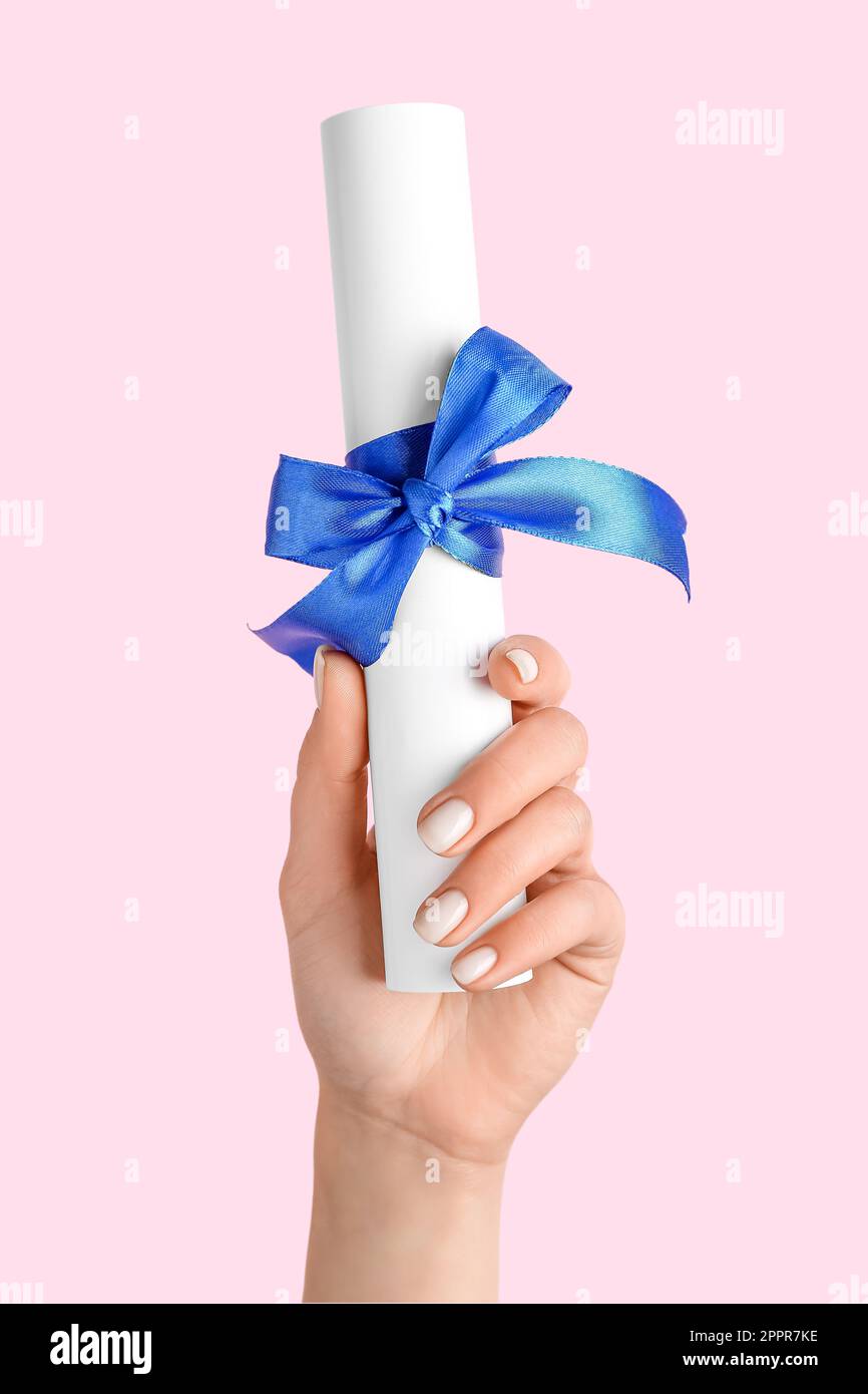 Woman holding diploma with ribbon on pink background Stock Photo - Alamy