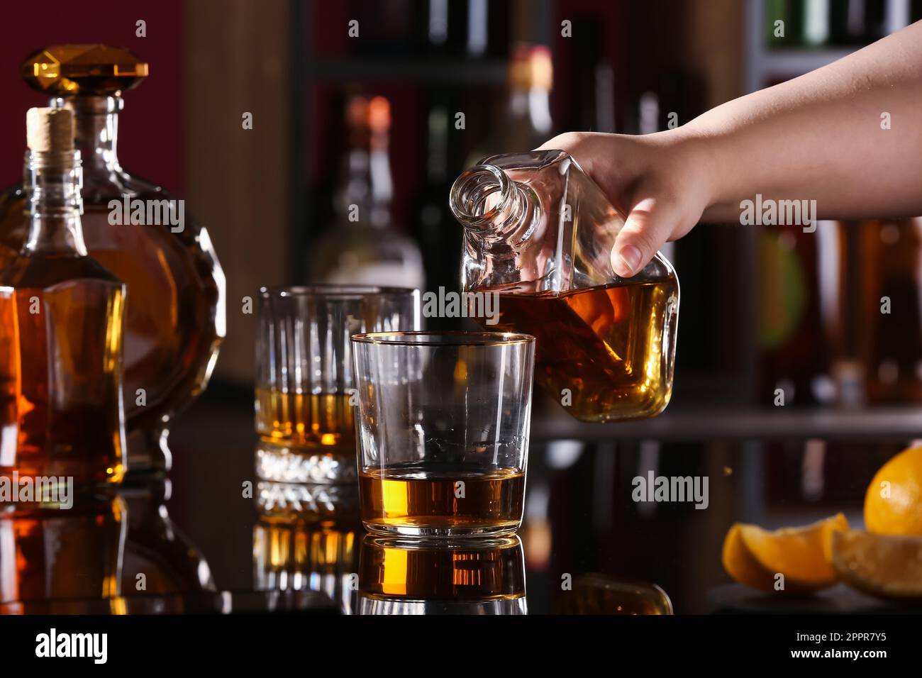 Woman pouring tasty rum from bottle into glass at table in bar Stock ...